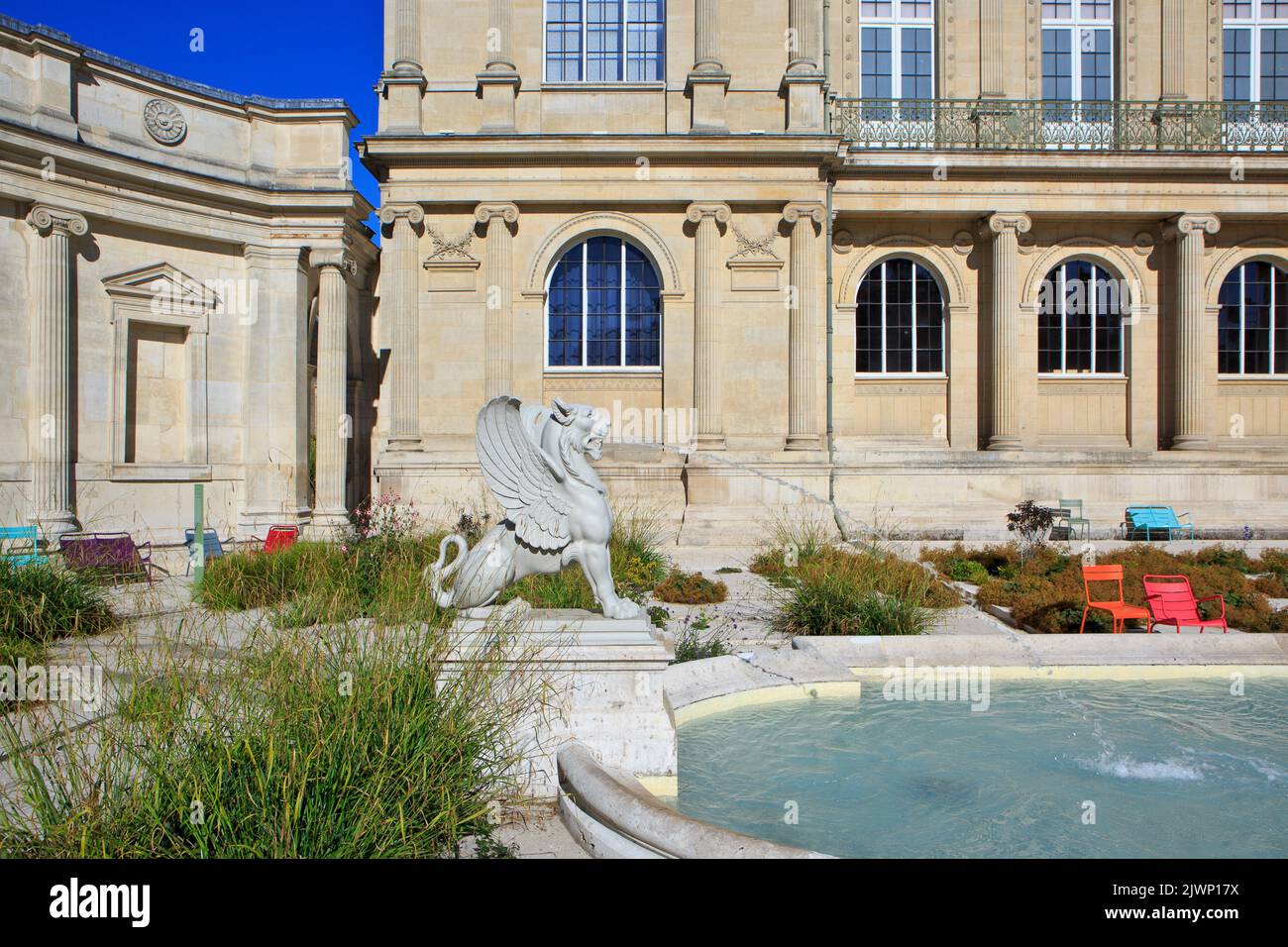 A statue of a griffin spouting water in a small pond in the gardens of ...