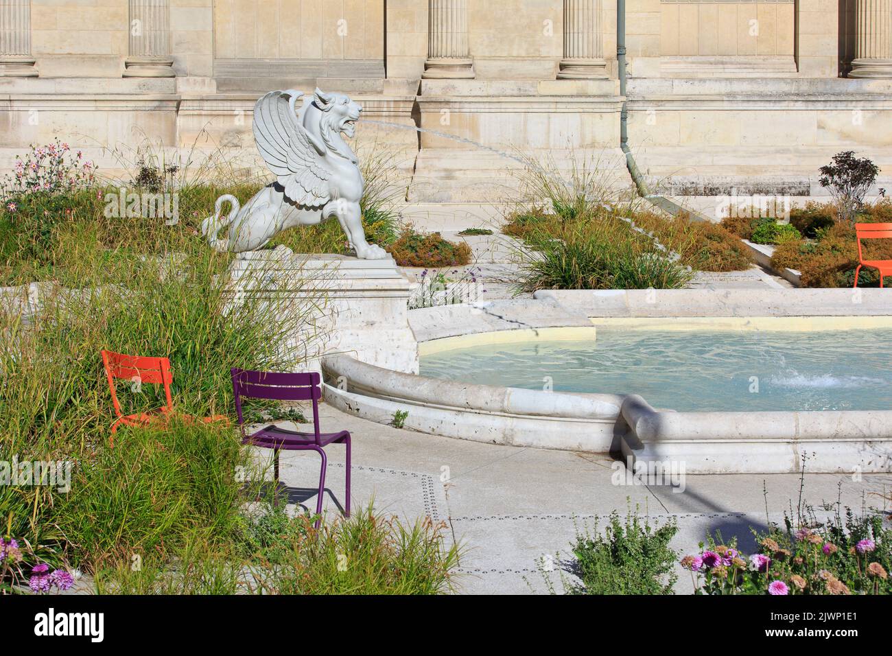 A statue of a griffin spouting water in a small pond in the gardens of ...