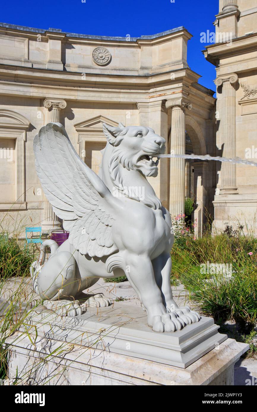 A statue of a griffin spouting water in a small pond in the gardens of ...