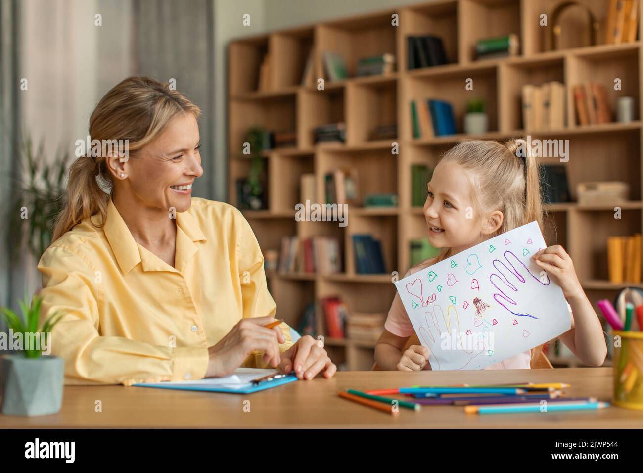 Cute little girl showing woman psychologist her drawing, kid having ...