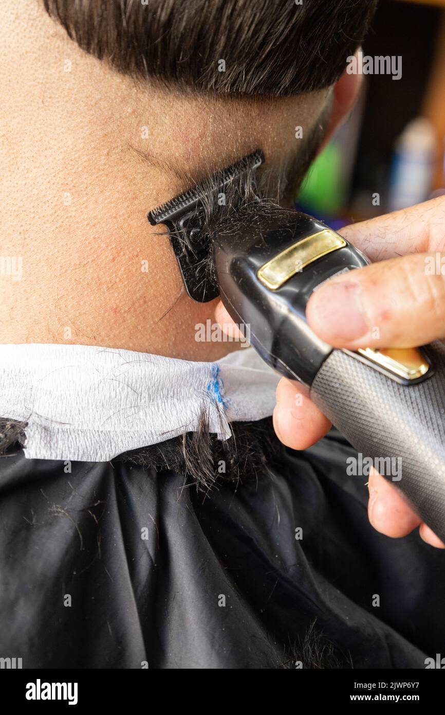 hands of a professional using a razor to design a modern haircut ...