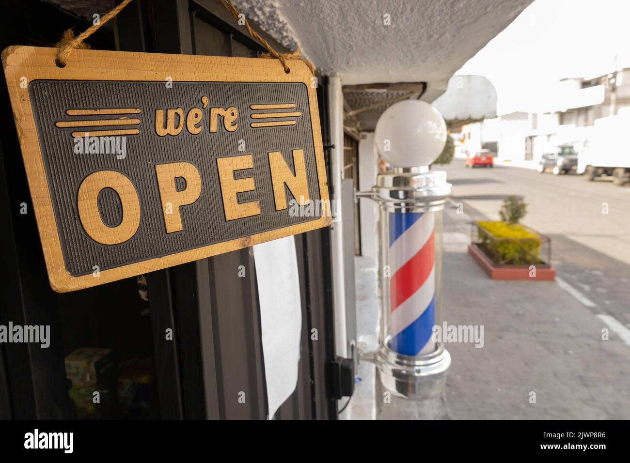 open business sign next to a barber pole decorating the entrance of a ...