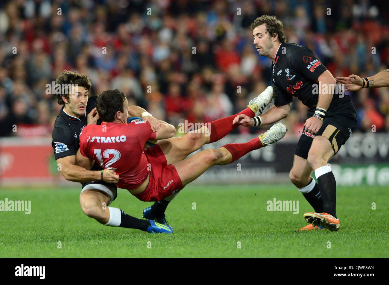Queensland Reds player Mike Harris (centre) is being tackled during ...