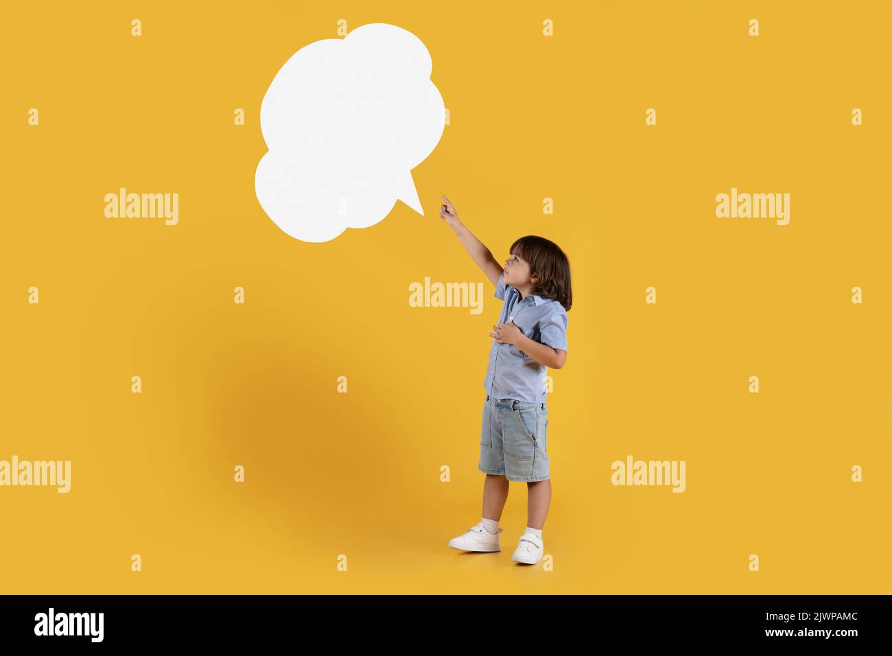 Adorable little boy pointing at empty speech bubble, feeling excited of ...