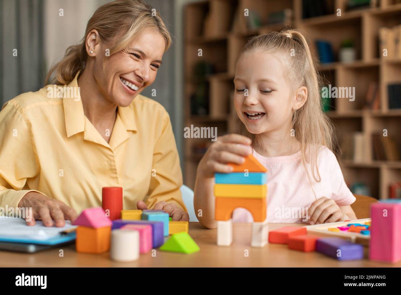 Pretty kid little girl and female child development specialist woman ...