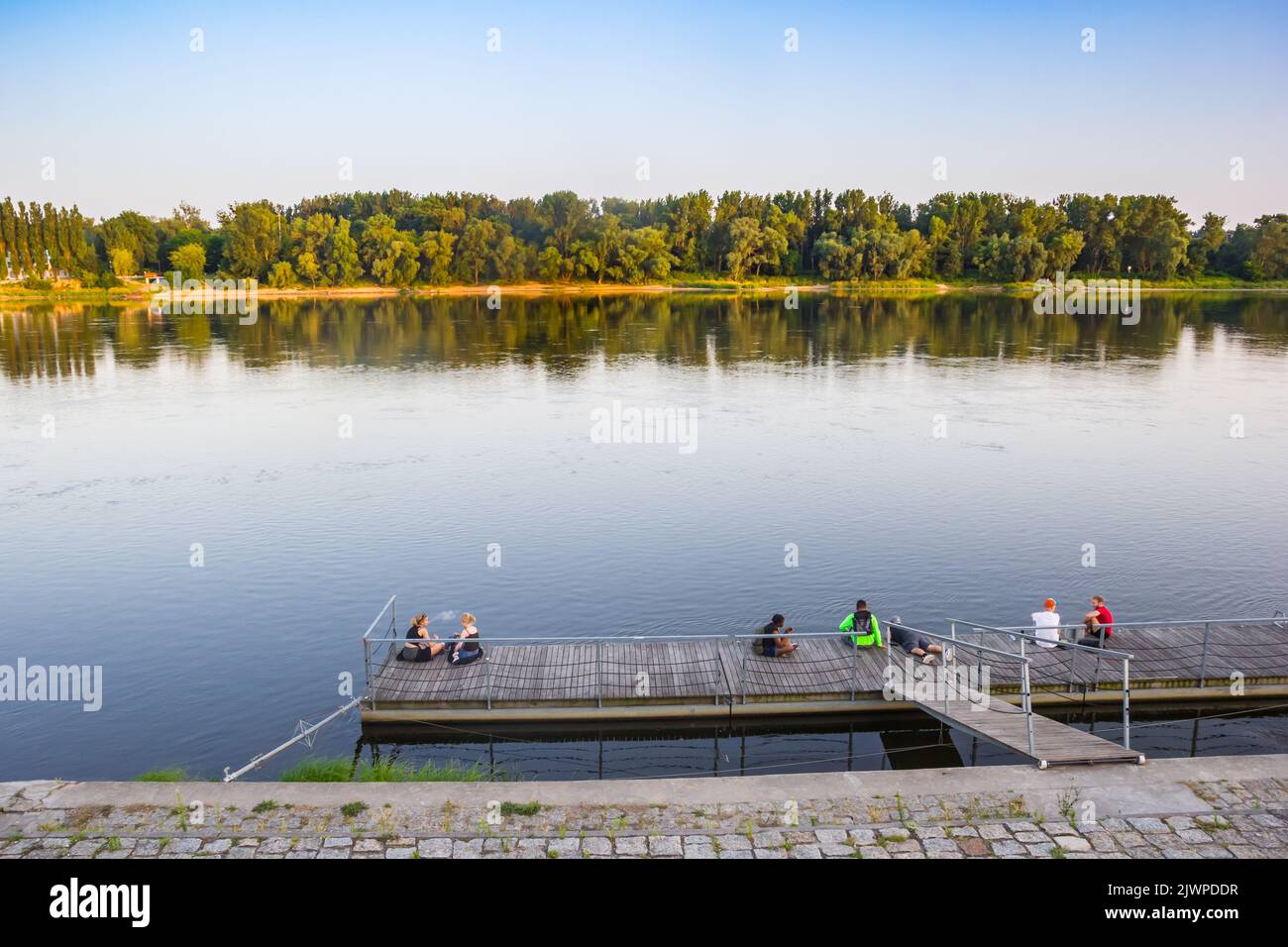Young people relaxing on the jetty at the Wisla river in Torun, Poland ...