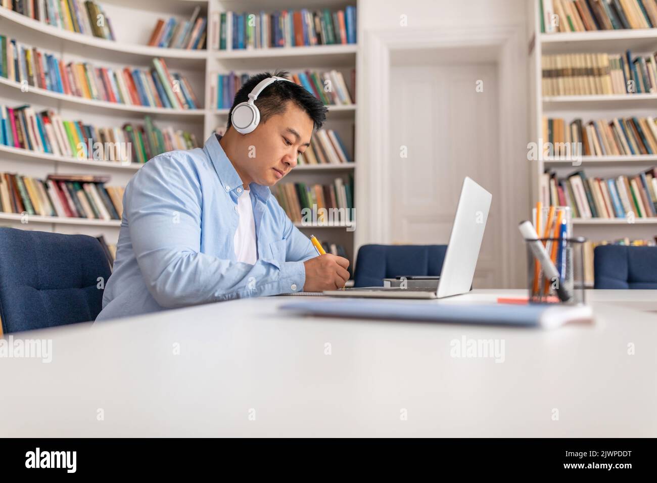 Korean Man Working Online On Laptop Taking Notes Indoor Stock Photo - Alamy