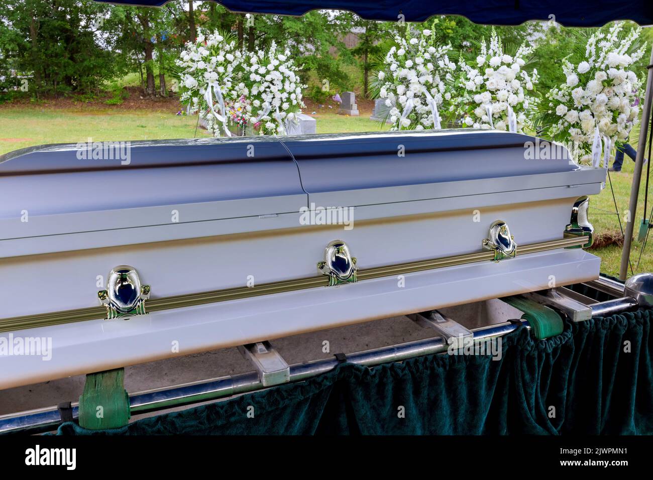 A funeral service is held in a cemetery followed by the coffin being ...