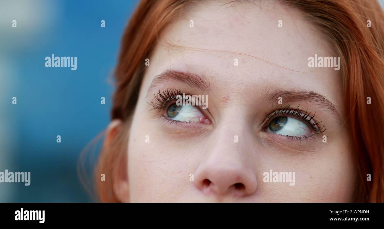 Pensive Woman thinking, eyes looking up. Closeup of redhair girl ...