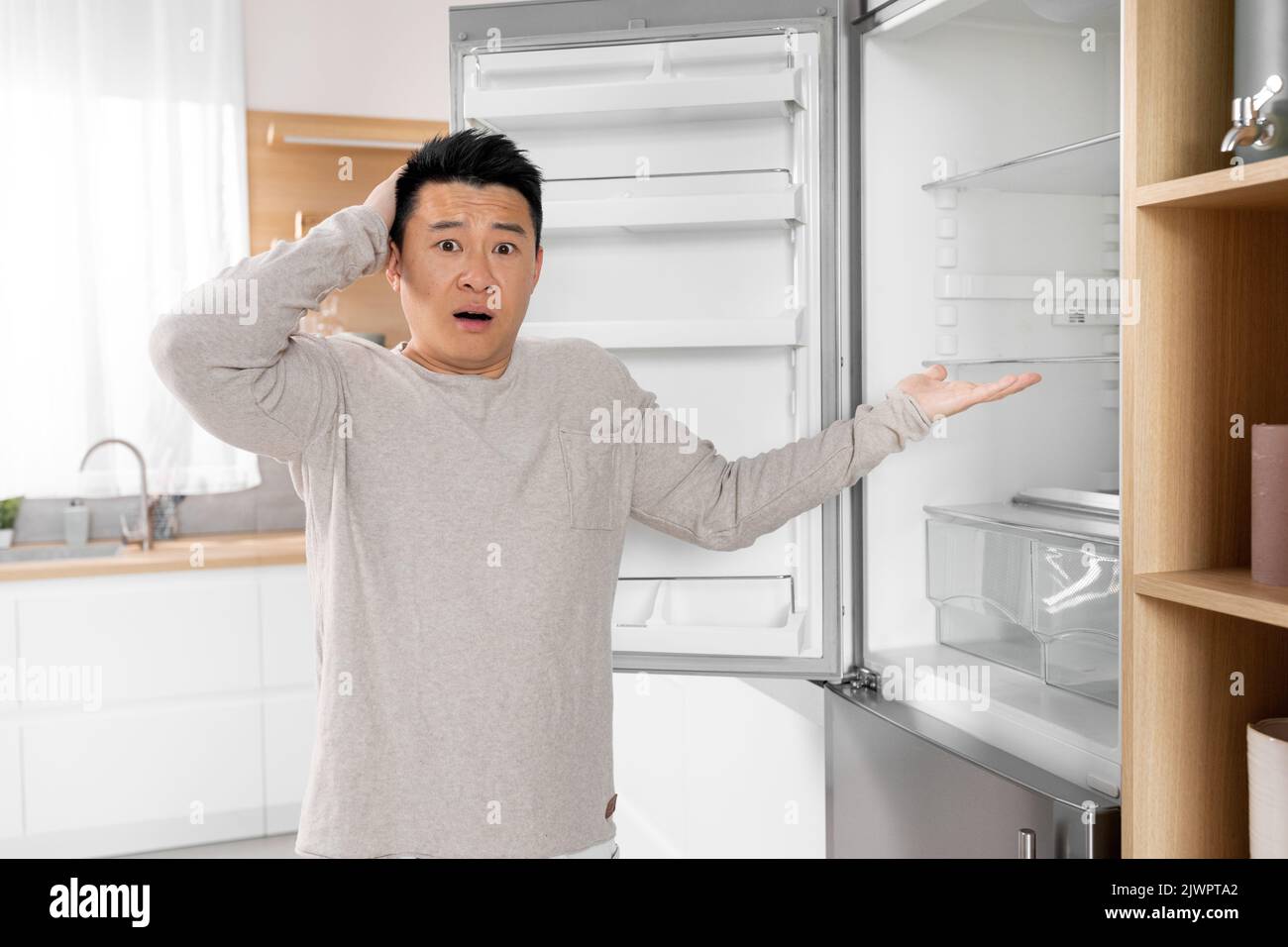 Shocked asian man pointing at empty fridge Stock Photo - Alamy