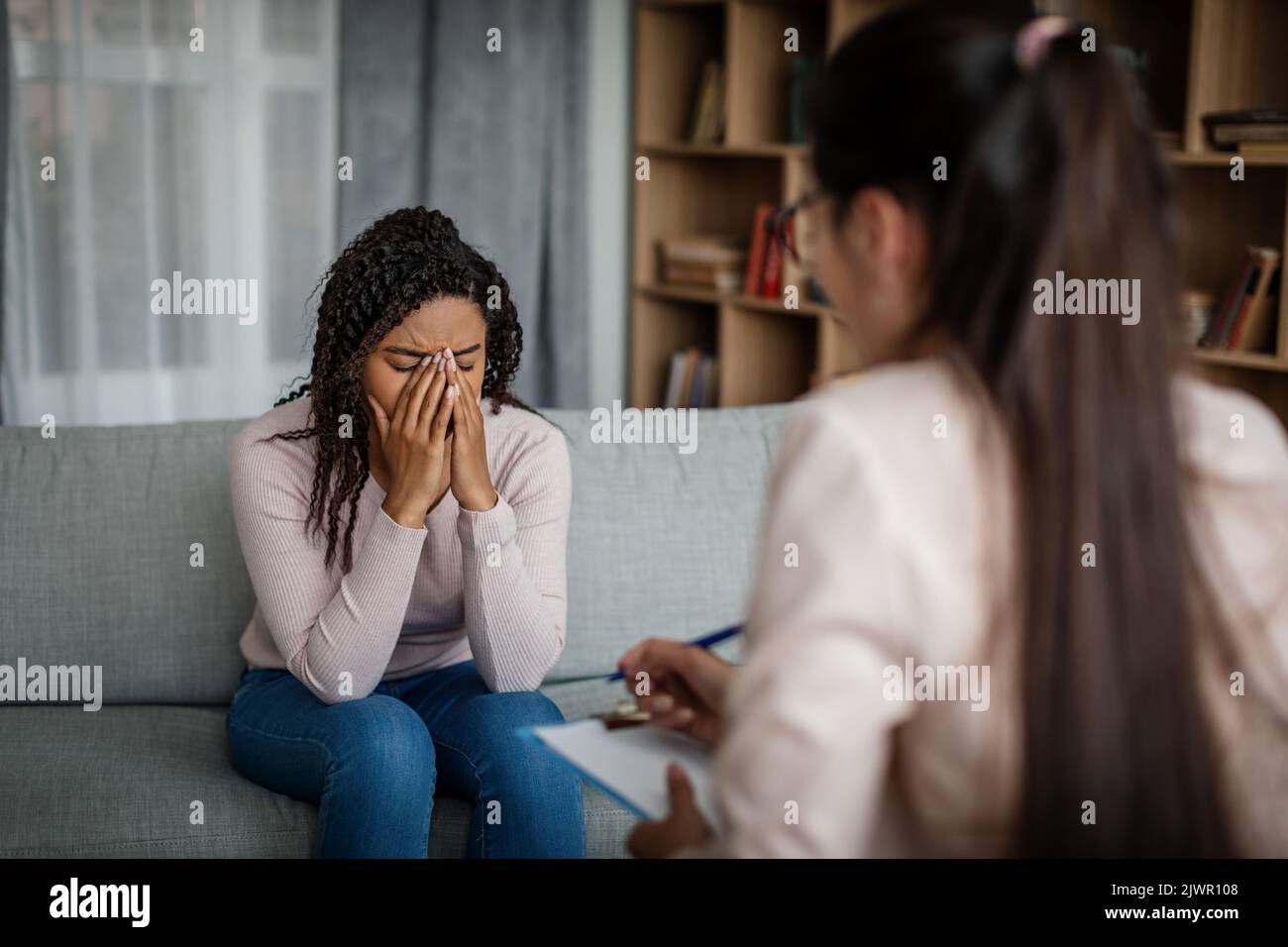 Sad crying black millennial female patient talking with european doctor ...