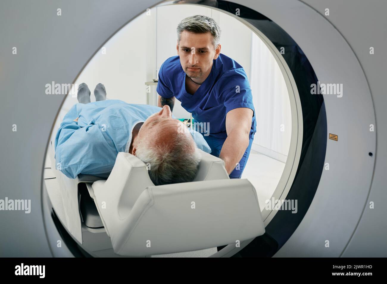 Senior man going into CT scanner. CT scan technologist overlooking ... Senior man going into CT scanner. CT scan technologist overlooking ...