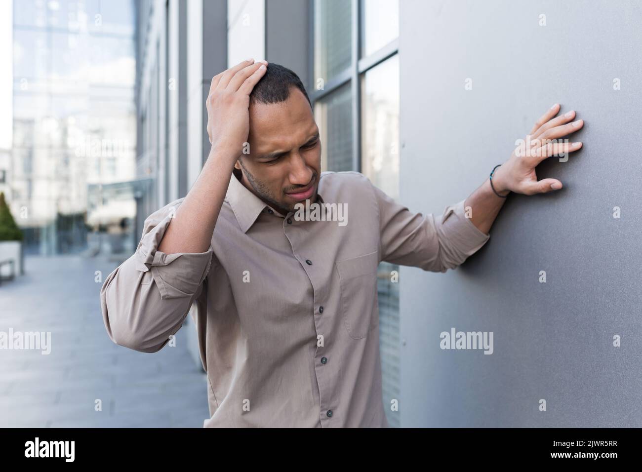 Sick african american man outside modern office building, man has ...
