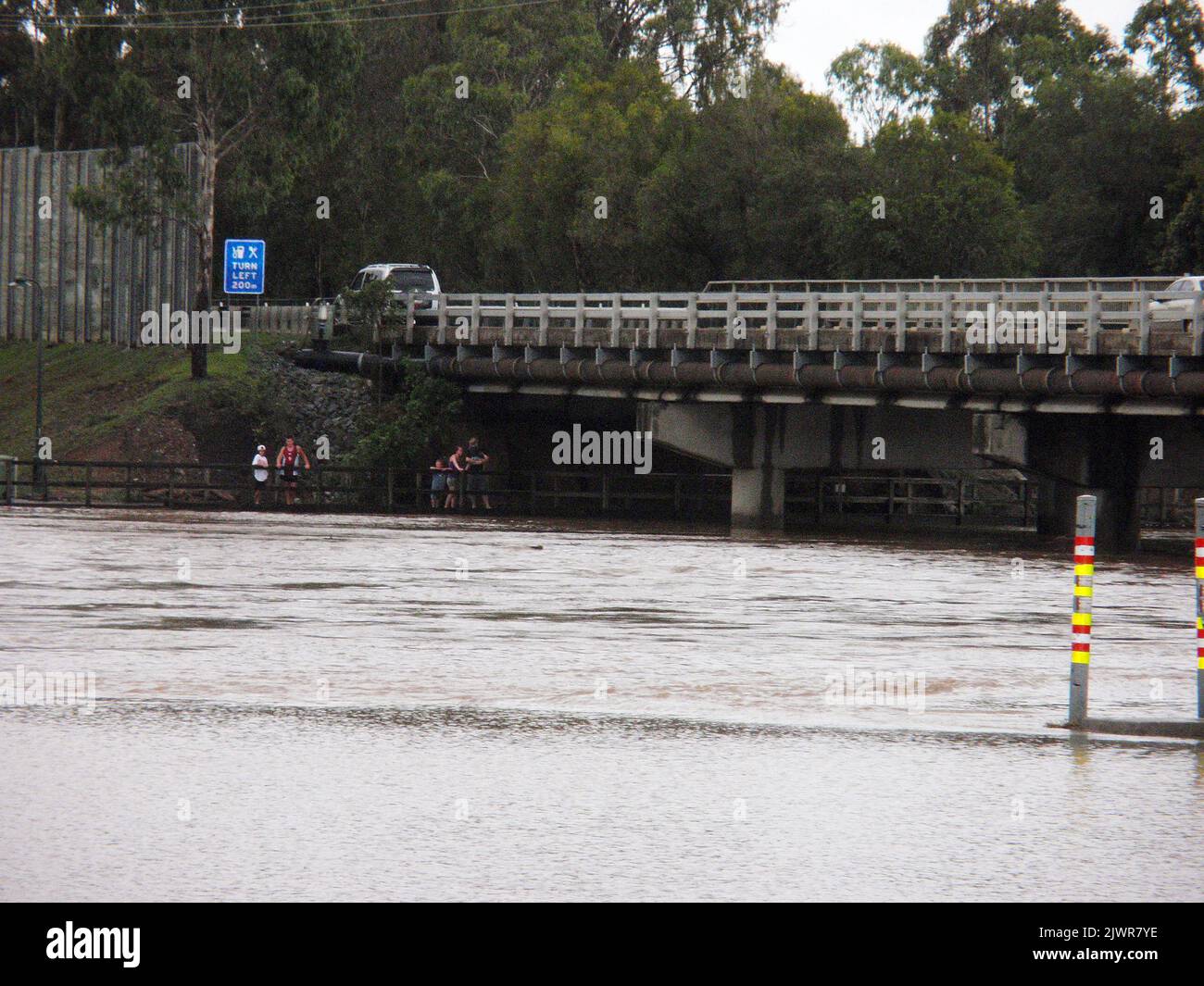 Locals watch floodwaters surge down the swollen Coomera River in ...