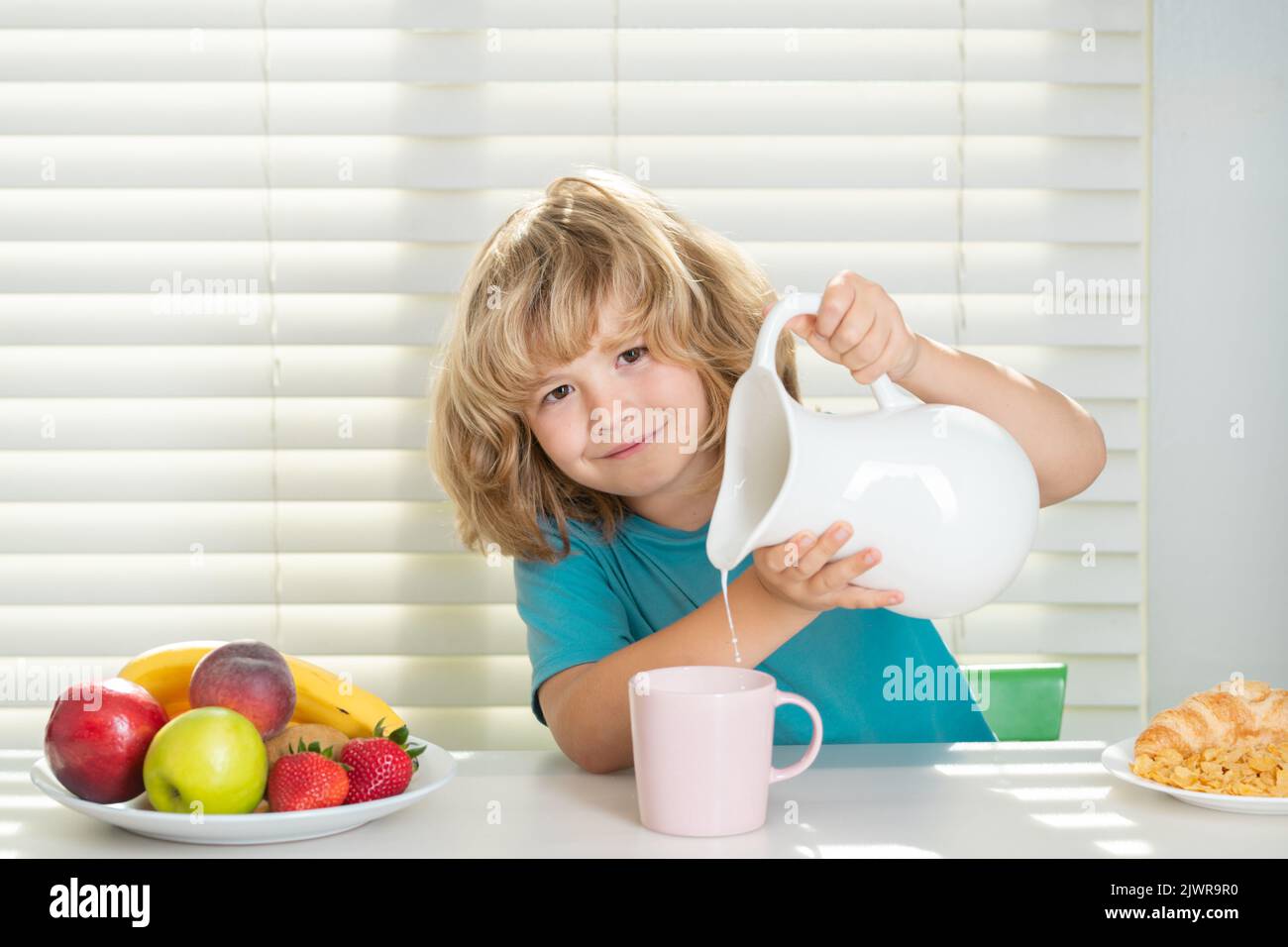 Kid boy pouring whole cows milk. Kid eating healthy food vegetables ...