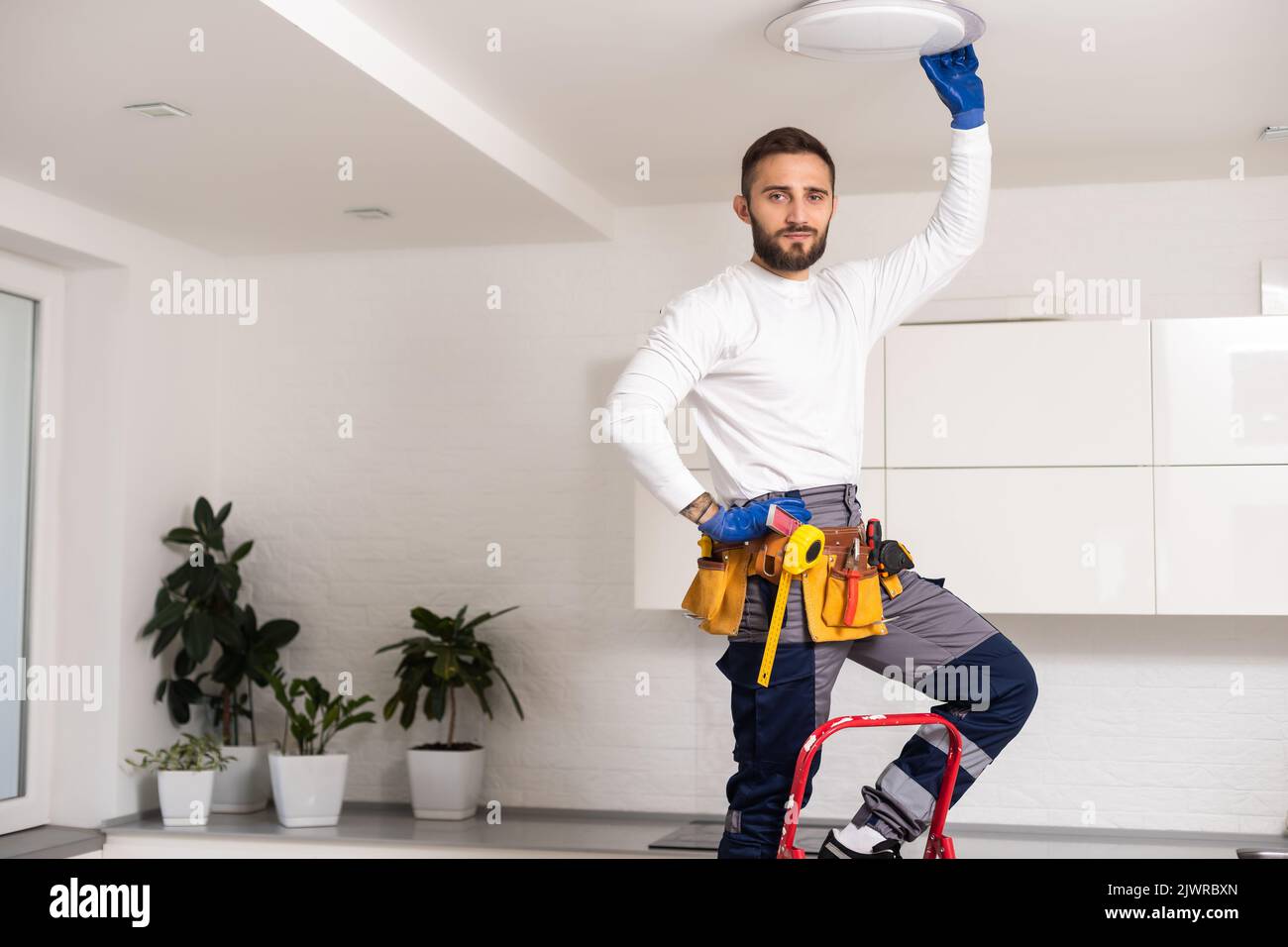 Electrician worker man assembling electric lamps in new apartment Stock ...
