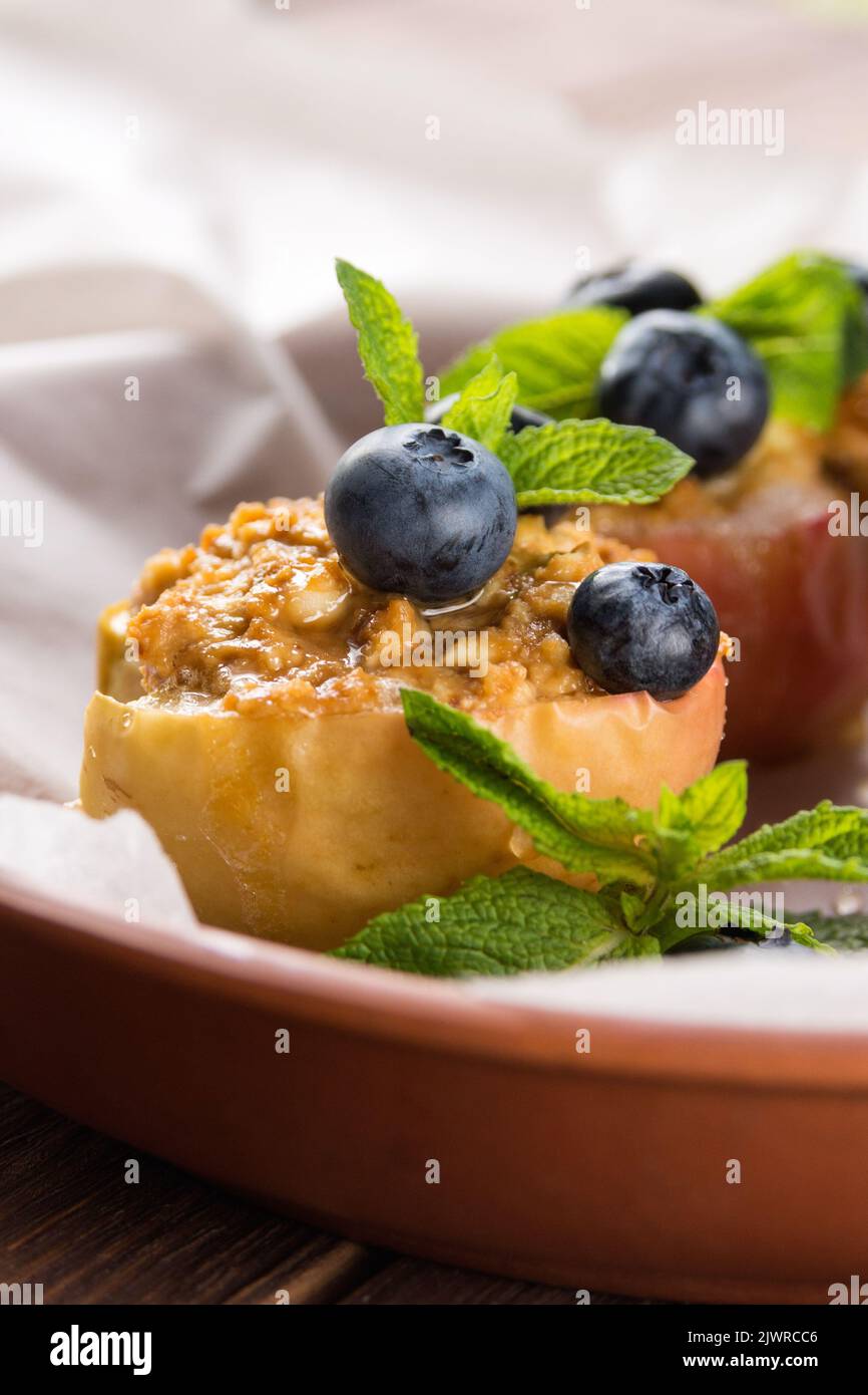 Blueberries on a baked apple in an oven with syrup, cinnamon and mint ...
