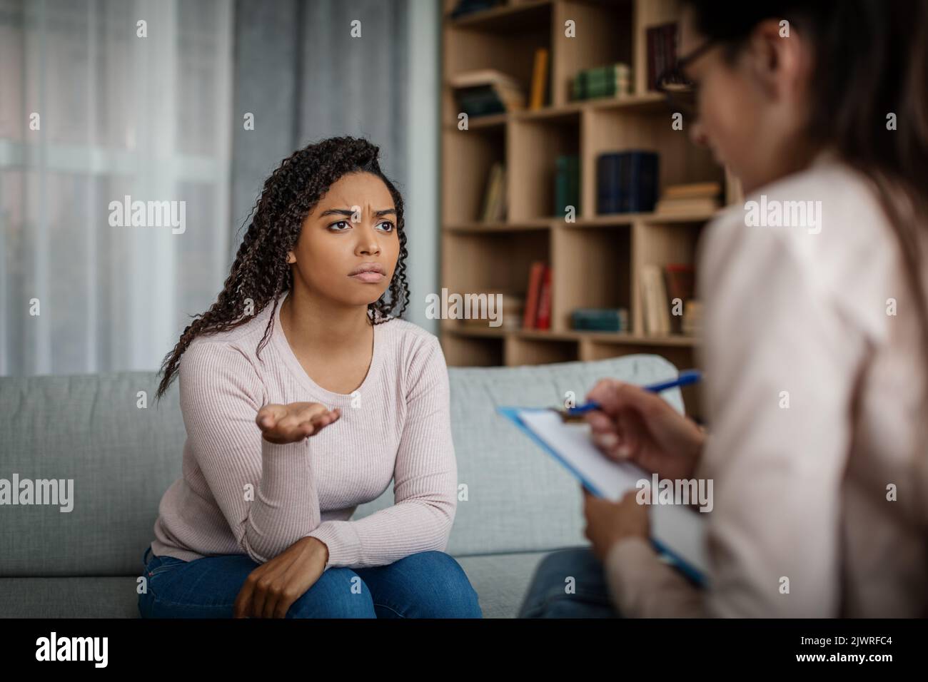 Unhappy sad black millennial woman patient talking with european doctor ...