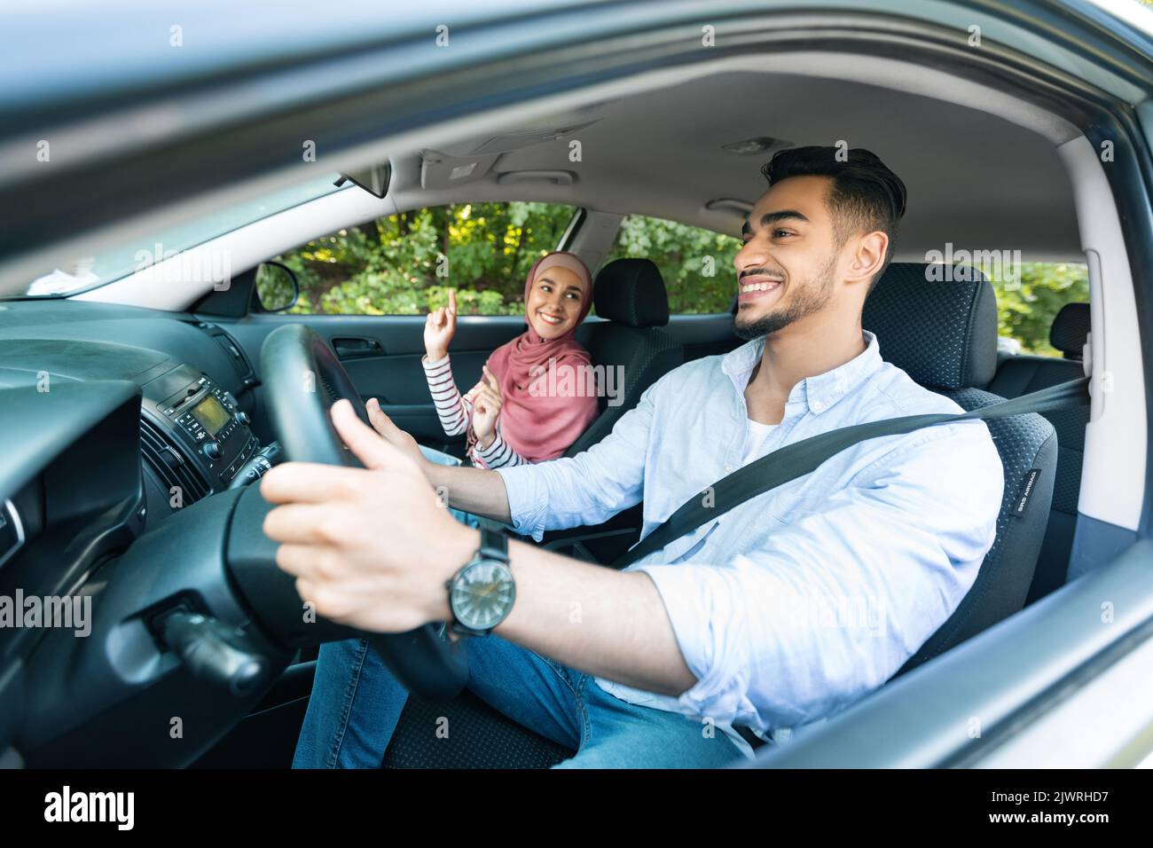 Cheerful Millennial Middle Eastern Guy Driving Car With Lady In Hijab