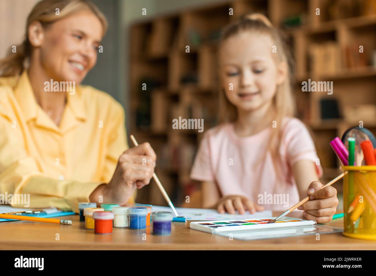 Art development for kids. Little girl painting with teacher at ...