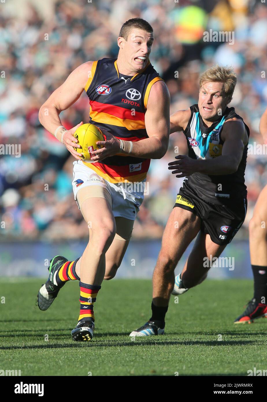 Josh Jenkins of Adelaide Crows steps a tackle from Kane Cornes of Port ...