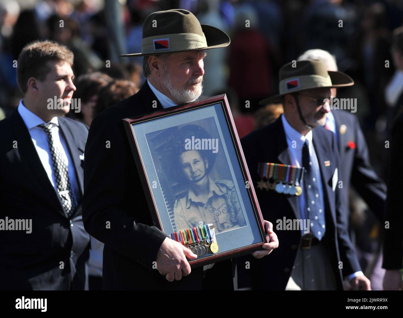A man carrying a photographic portrait and medals of a serviceman march ...