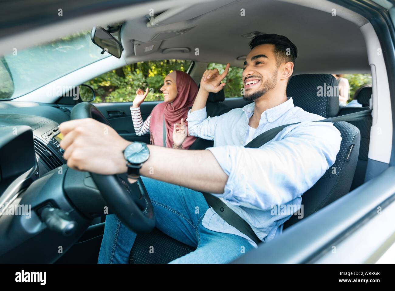 Cheerful Glad Young Arab Man Driving With Female In Hijab Ride In Car