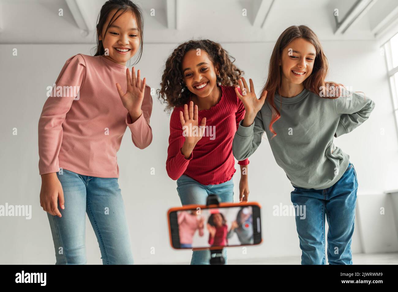 Three Happy Diverse Girls Waving Hands To Smartphone Indoors Stock ...