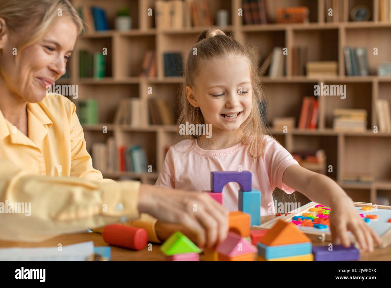 Friendly child development specialist observing girl preschooler ...