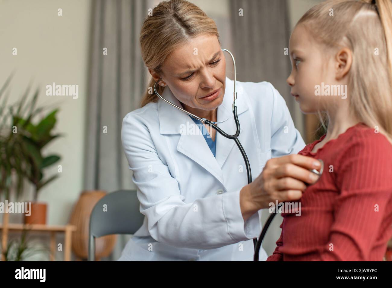 Worried pediatrician doctor examining little girl's heart beat and ...