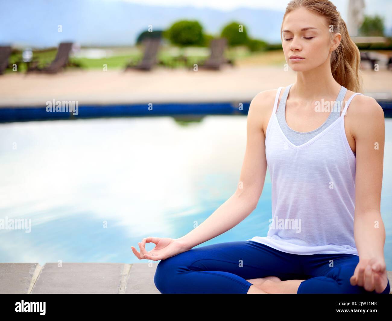 Finding her inner calm. a young woman doing yoga next to a swimming ...