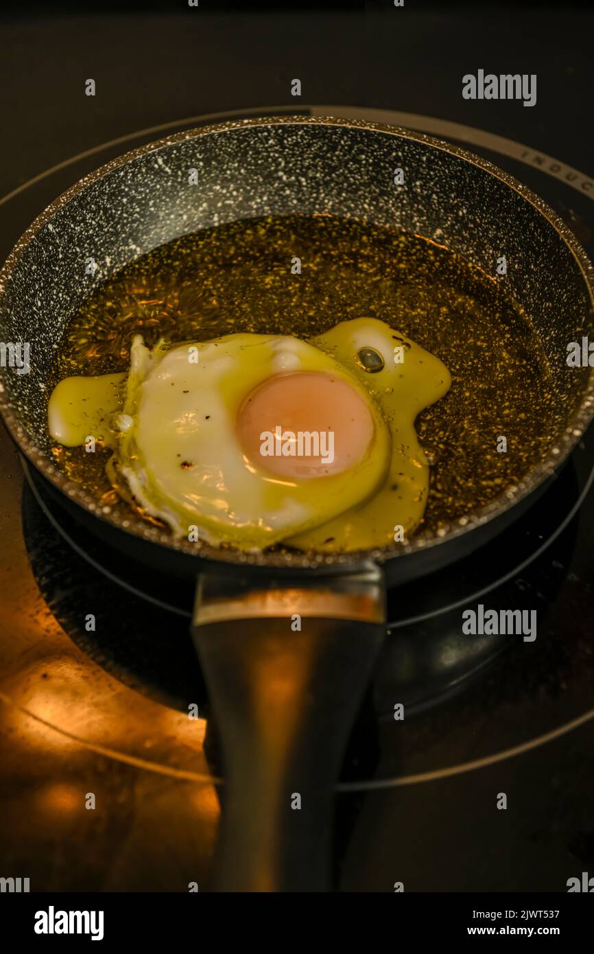 A fried egg in a frying pan cooking with olive oil Stock Photo - Alamy