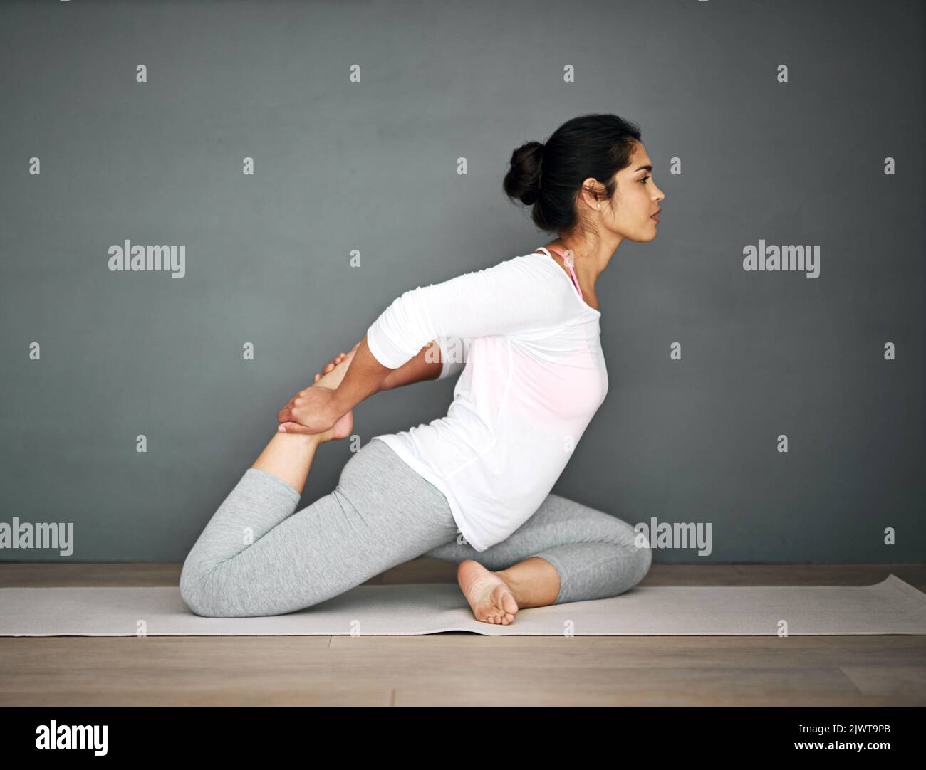 Yoga keeps her mind and body strong. a young woman stretching during ...