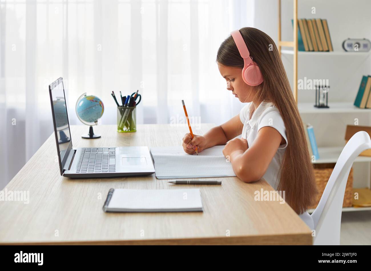 School child sitting at desk with laptop computer, studying online and ...