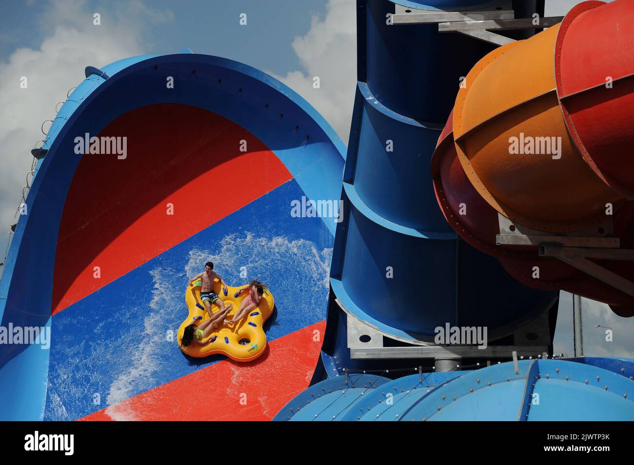 People ride a waterslide on opening day at the Wet N Wild theme park at ...