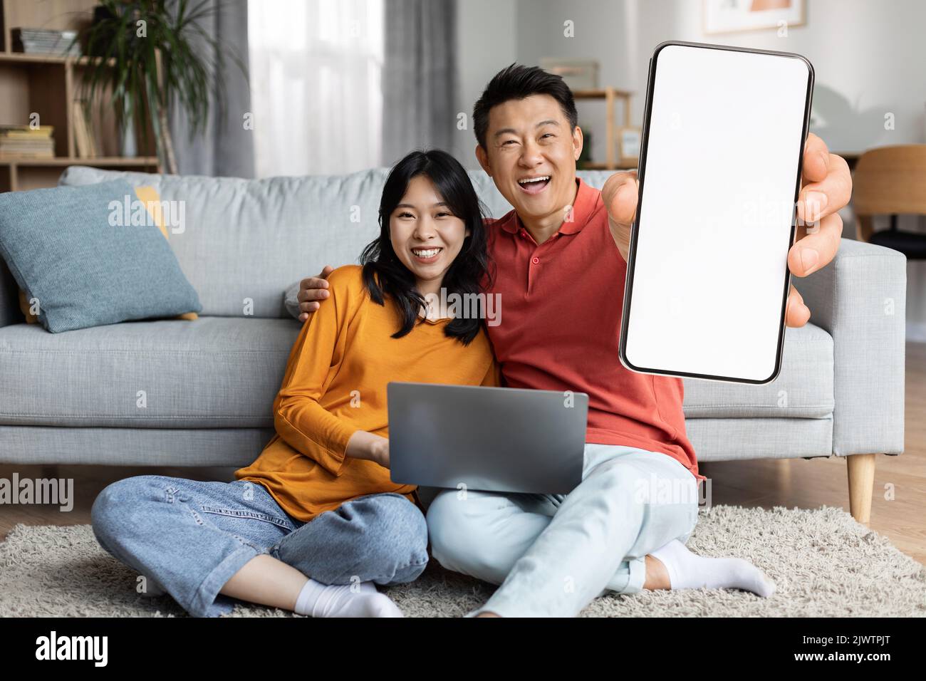 Emotional chinese couple chilling together at home, using gadgets Stock ...