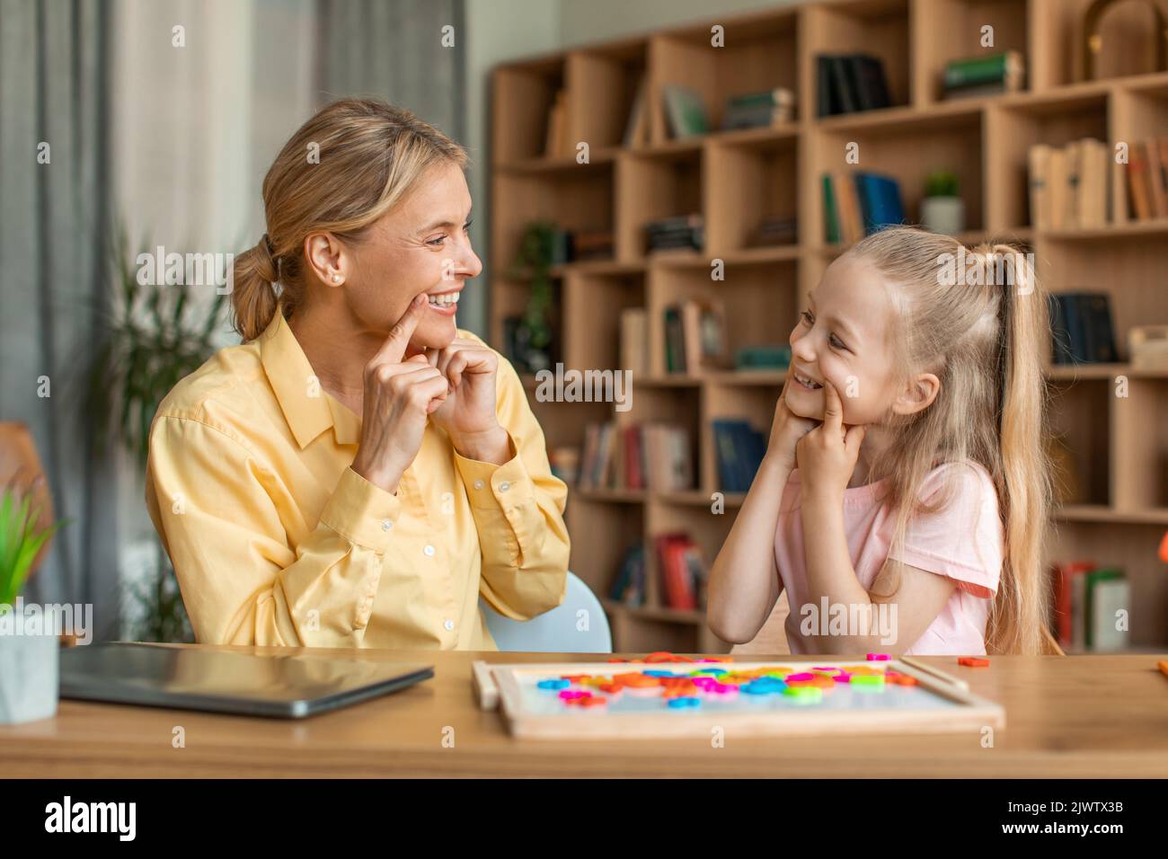 Female speech-language pathologist having lesson with little girl ...