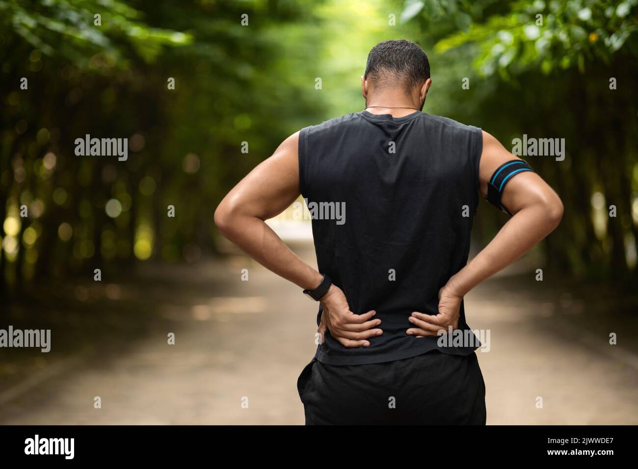 Back view of sportsman touching sore zone on his back Stock Photo - Alamy