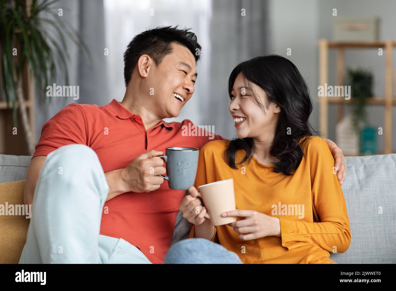 Portrait of positive asian lovers drinking tea, having conversation ...