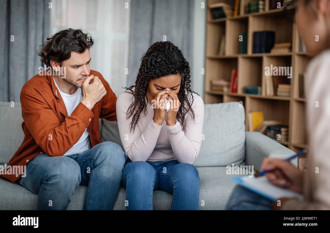 Despaired sad young european man calms black crying woman at meeting ...