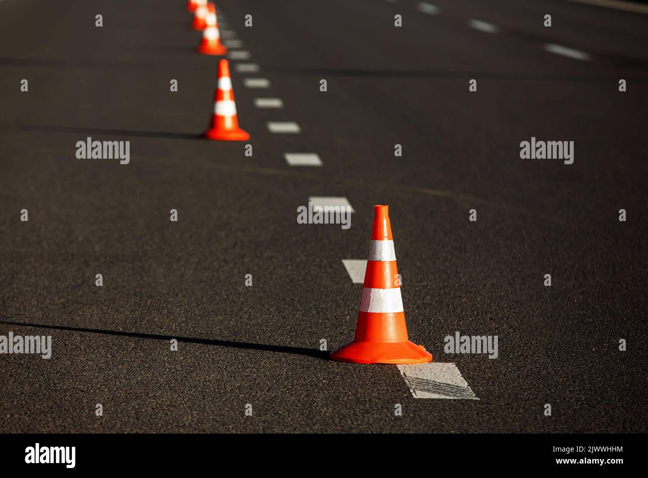 A row of traffic orange striped cones on the road. These objects are ...