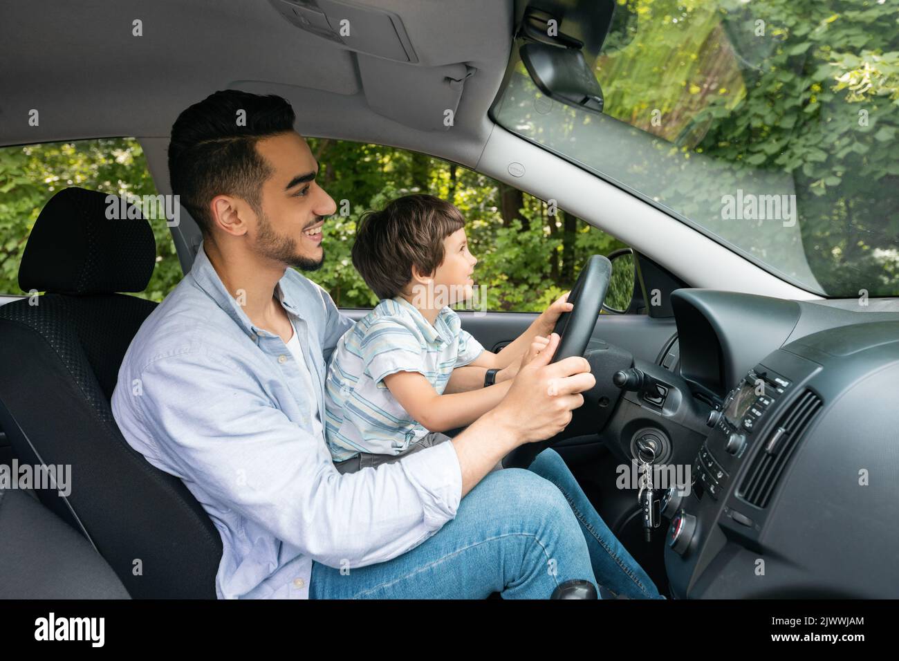 Happy smiling muslim young male teaches small kid how to drive, profile ...