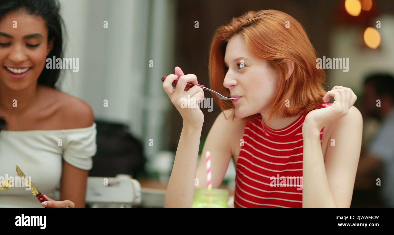 Two diverse multi-ethnic friends eating at restaurant Stock Photo - Alamy