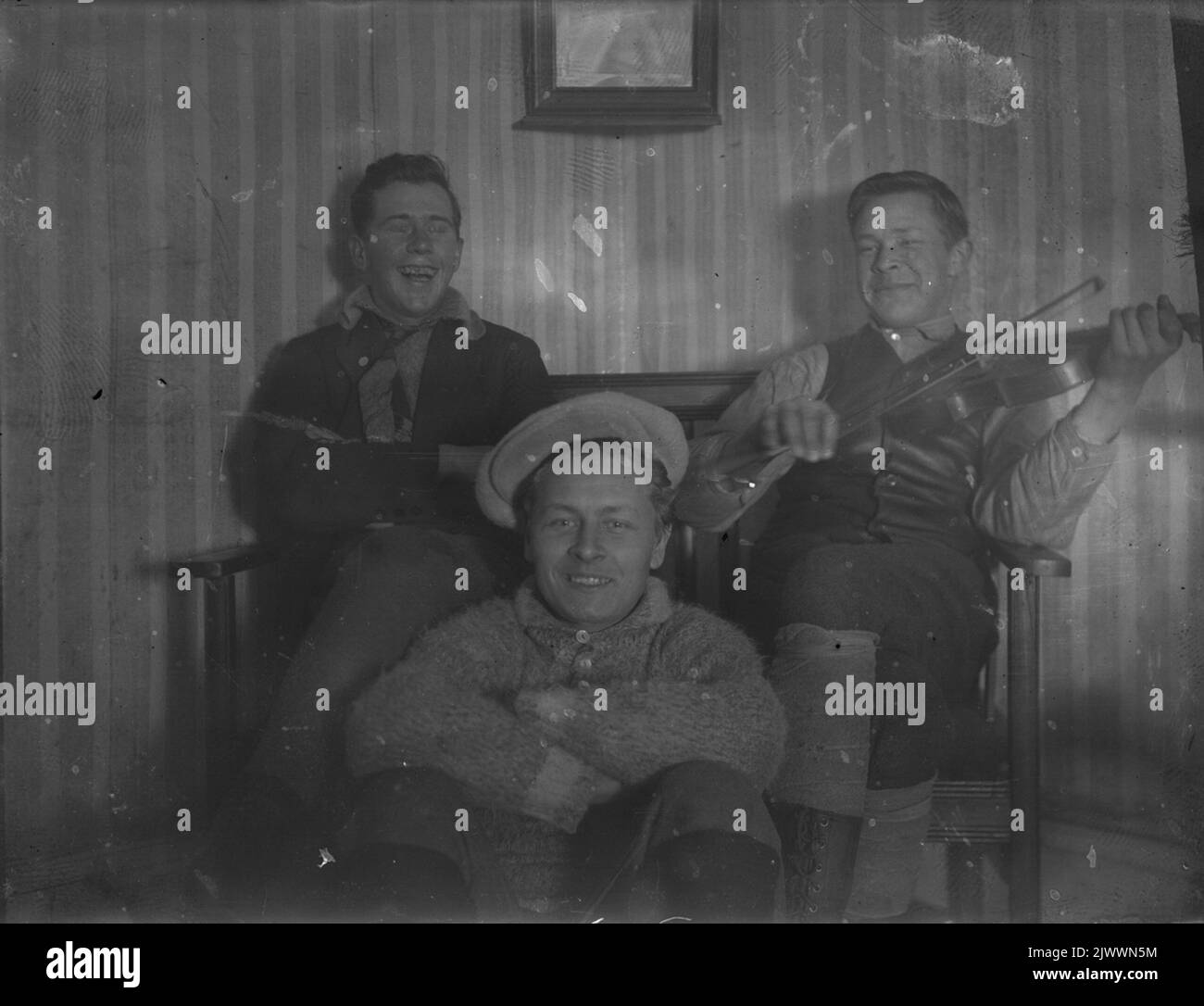 Three men, one plays violin. Tre män, en spelar fiol Stock Photo - Alamy