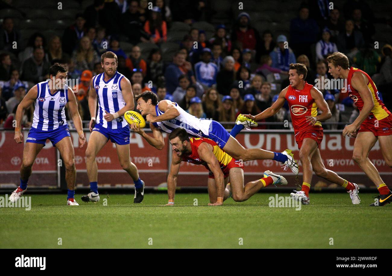 Joel Tippett of the Kangaroos handballs as he lands on the back of ...