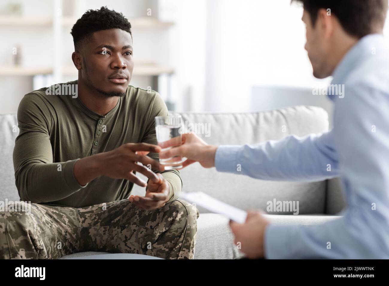 Therapist passing glass of water to his patient military man Stock ...