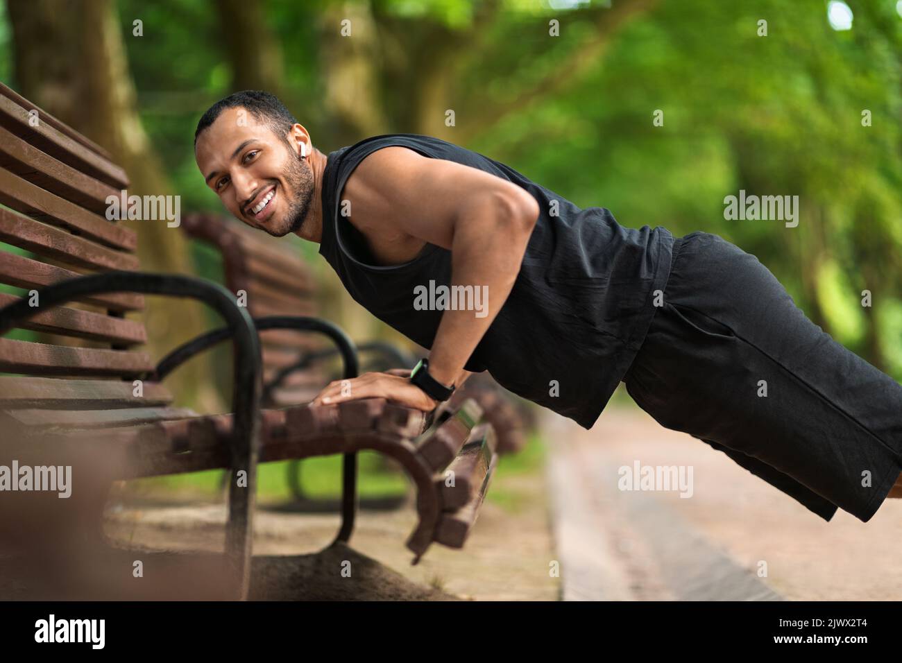 Sporty black guy having outdoor workout, pushing from bench Stock Photo ...