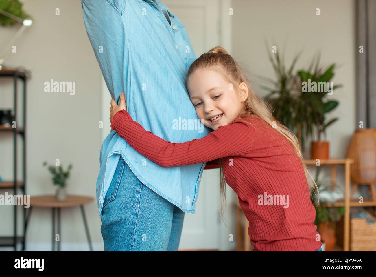 Cute little girl embracing mother's pregnant belly, happy child leaning ...