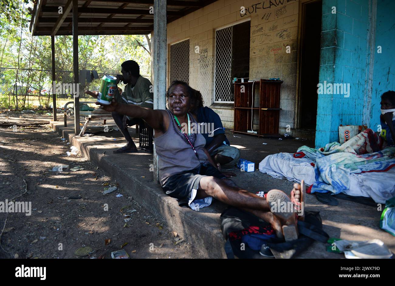 An aboriginal woman drinks beer while sitting outside a house in the ...