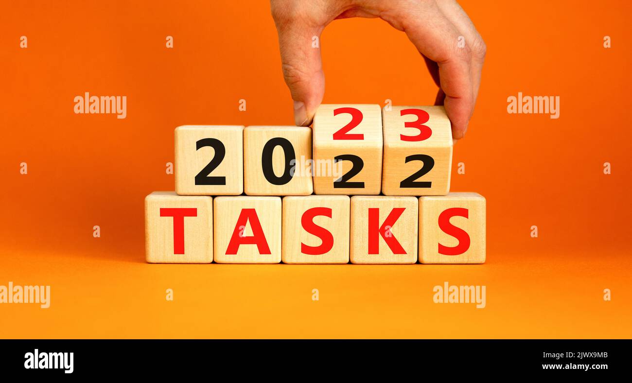 2023 tasks new year symbol. Businessman turns a wooden cube and changes ...